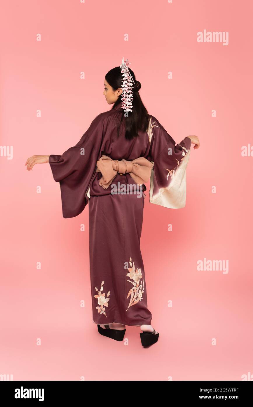 Side view of asian woman posing in traditional kimono on pink ...