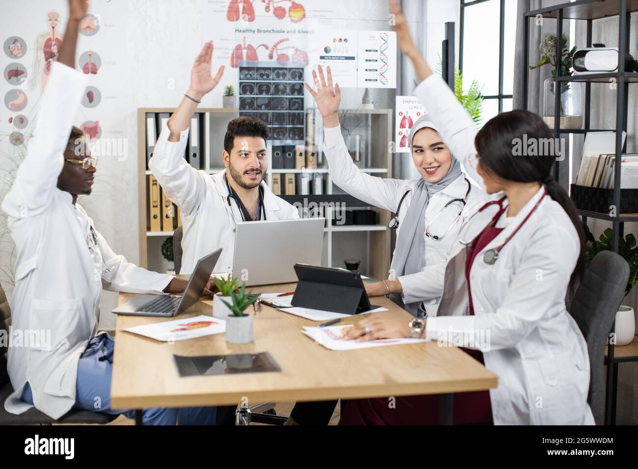 Team of four international doctors holding hands up for expressing ...