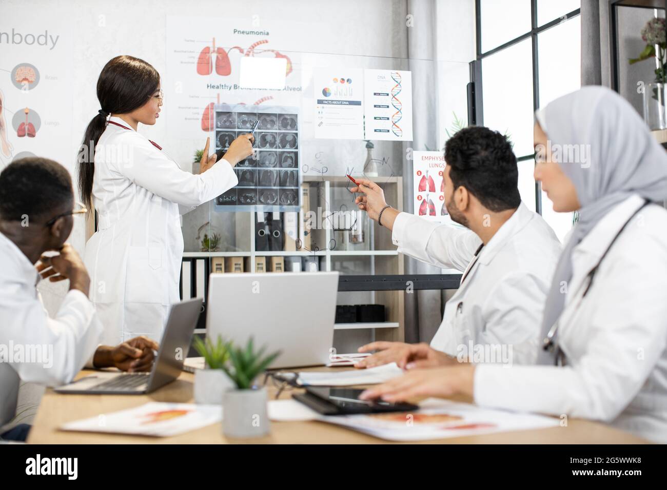 Group of four multiracial doctors using modern gadgets while examining ...