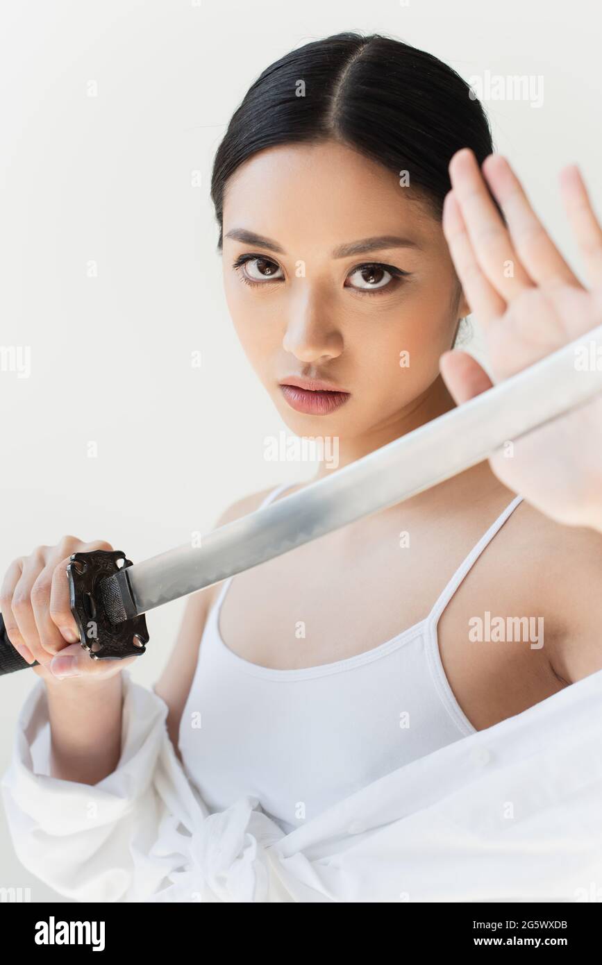 Young japanese woman touching sword on blurred foreground isolated on ...