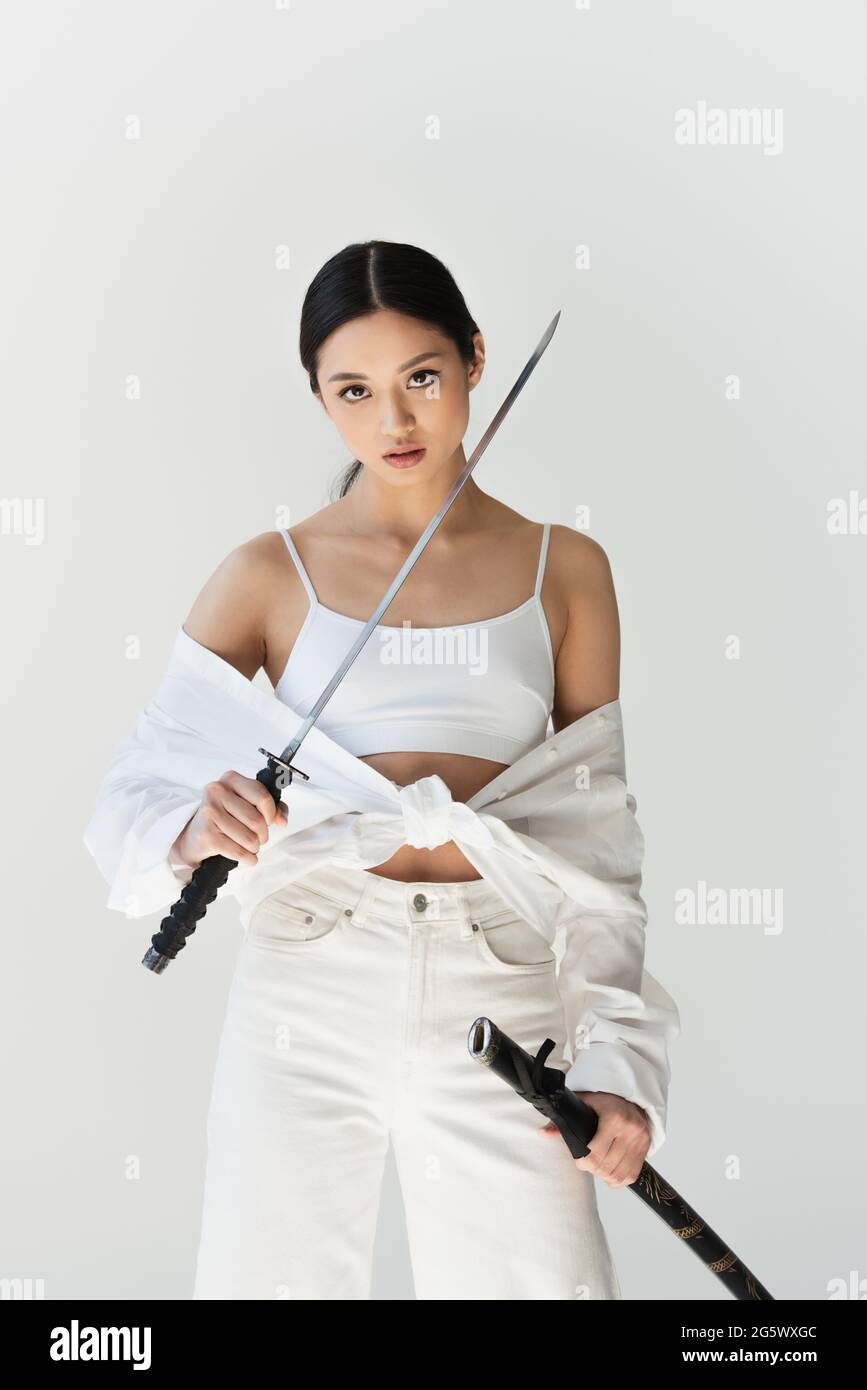 Young japanese woman with sheath and sword looking at camera isolated ...