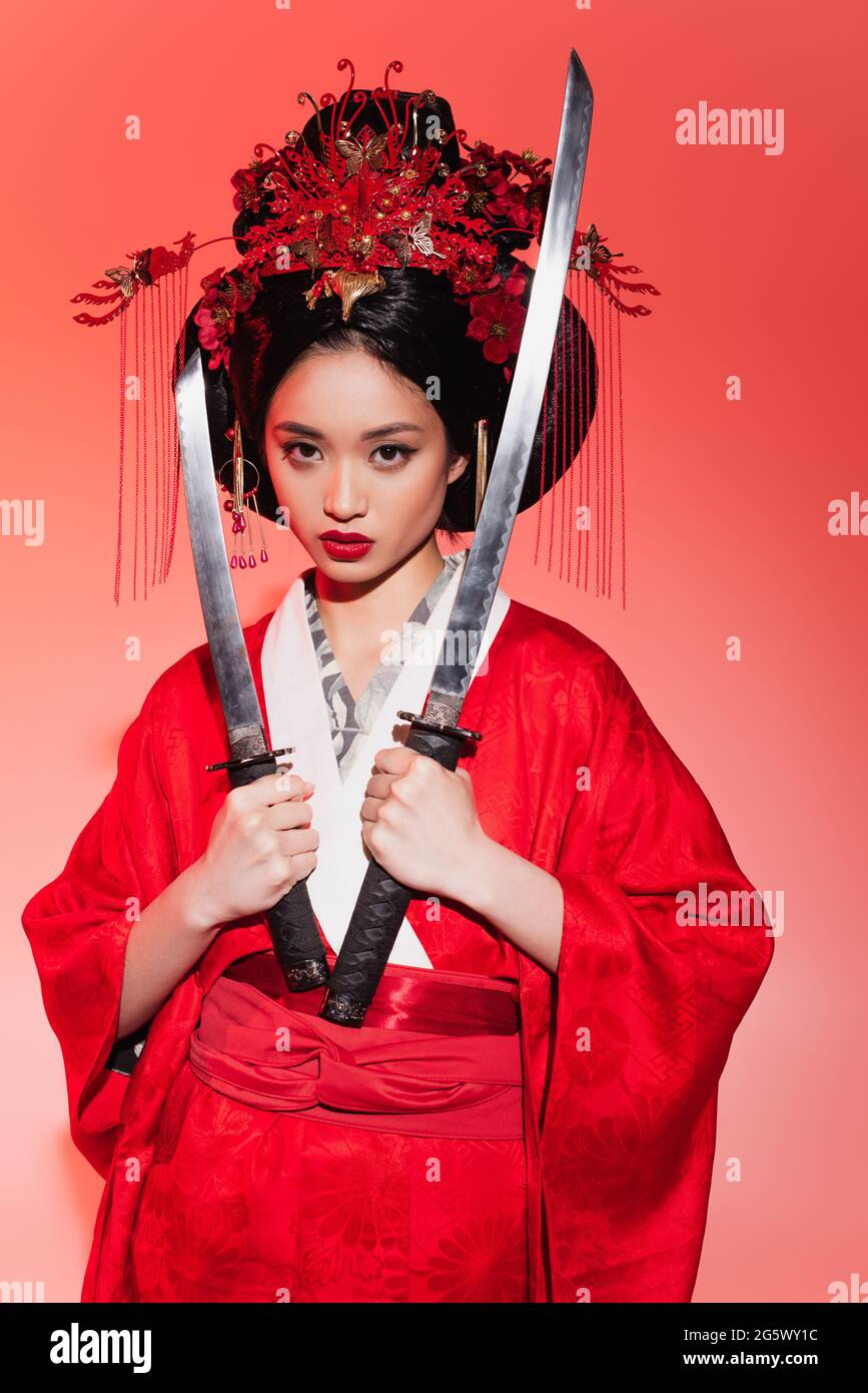 Japanese woman in traditional costume holding swords on red background ...