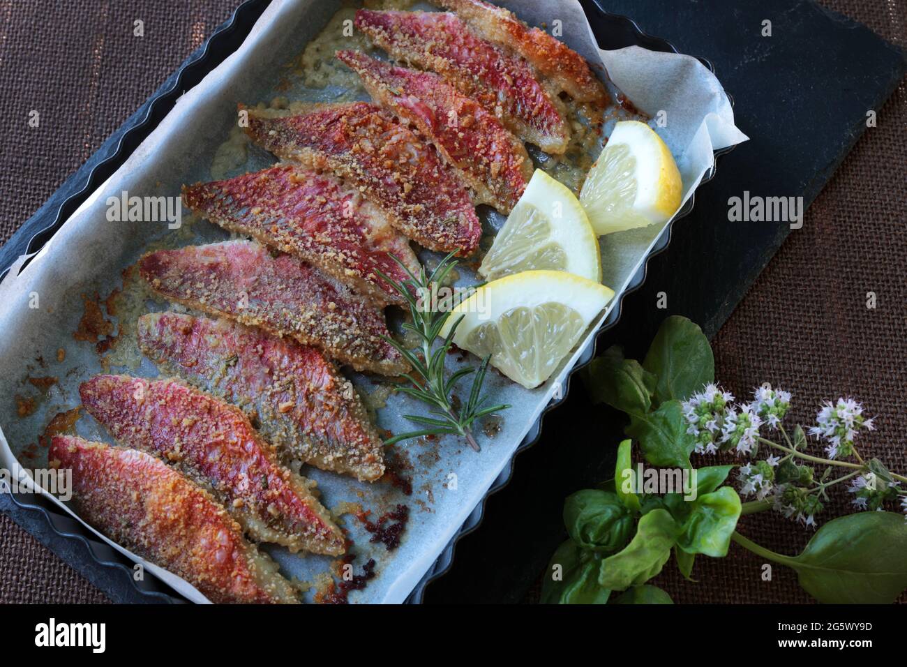 Baked gurnard fillet with lemon and herb on a tray. Directly above ...