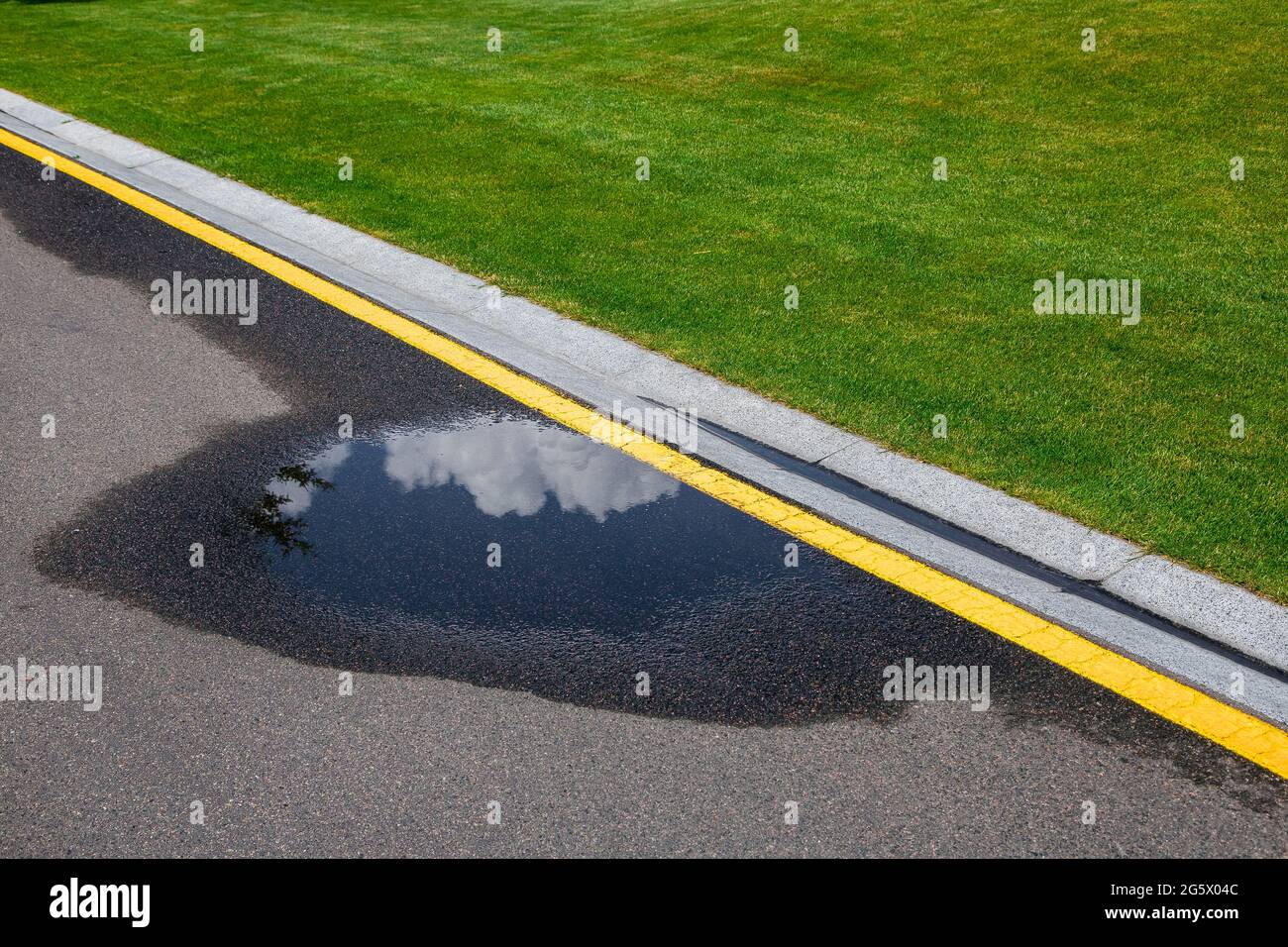 puddle on asphalt road with stormwater on the side of the road with a ...