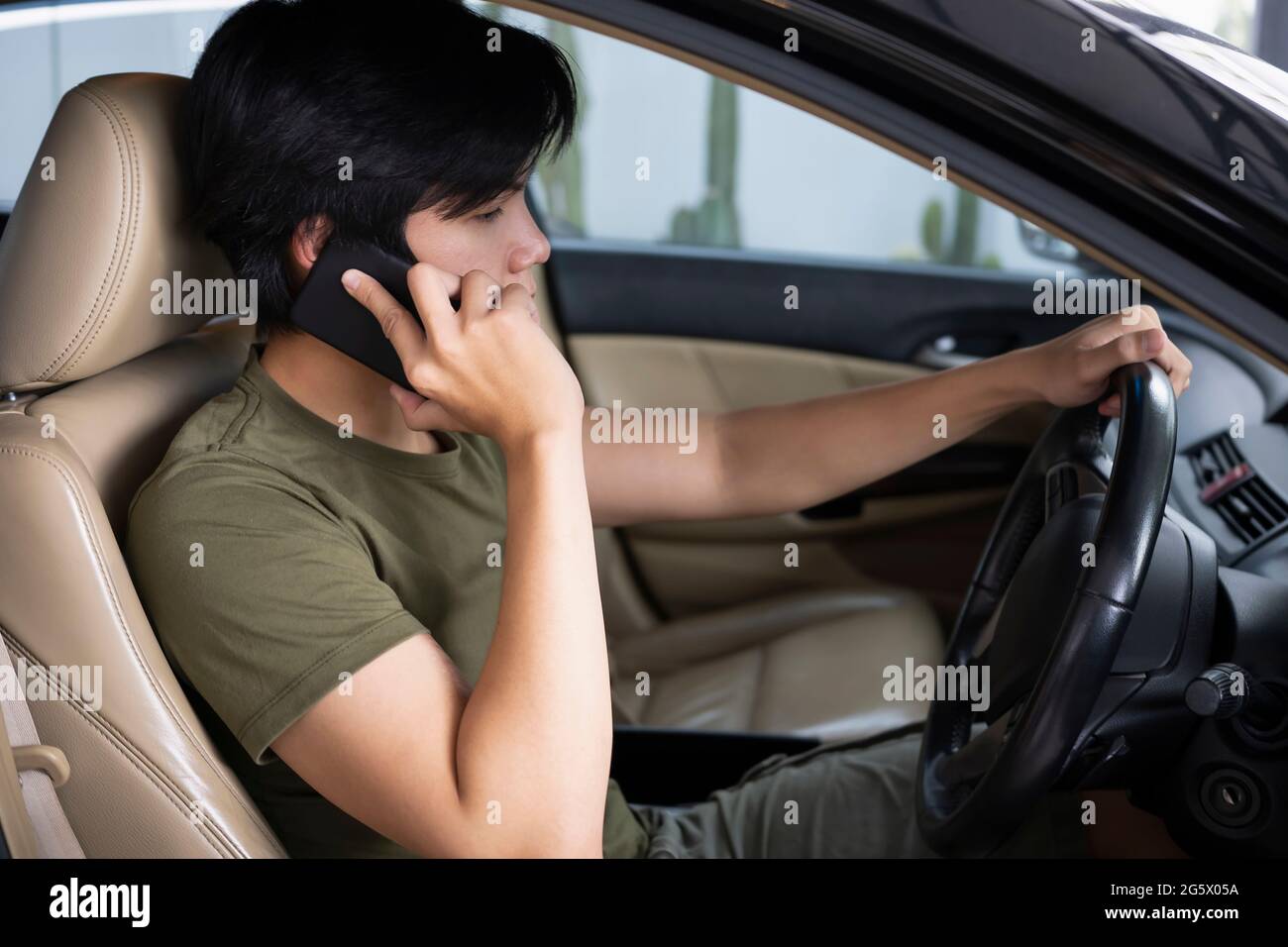 Young man talking on mobile phone while driving car Stock Photo - Alamy
