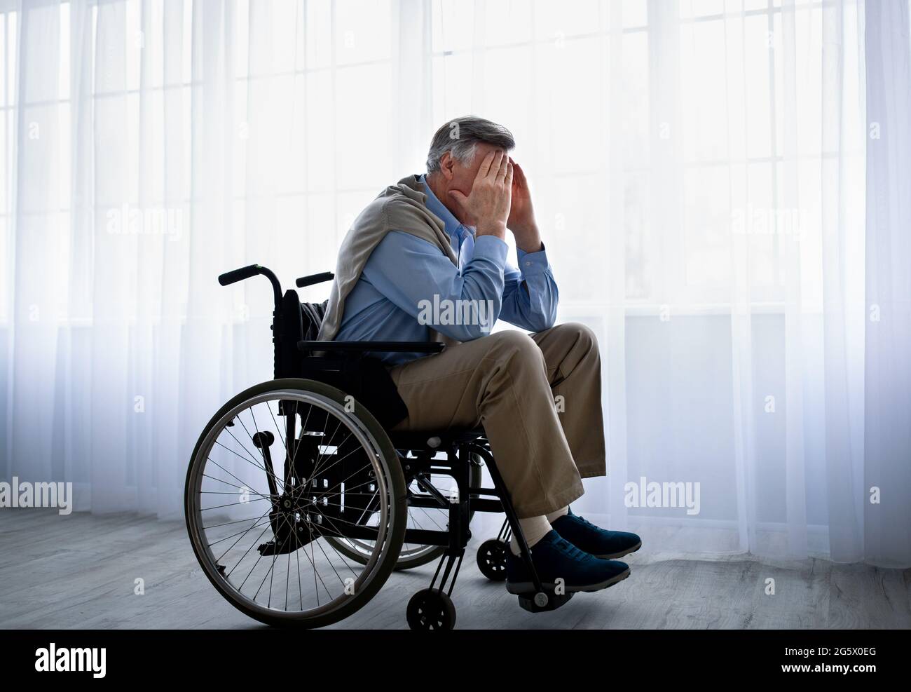 Elderly handicapped man in wheelchair covering face with hands, crying ...