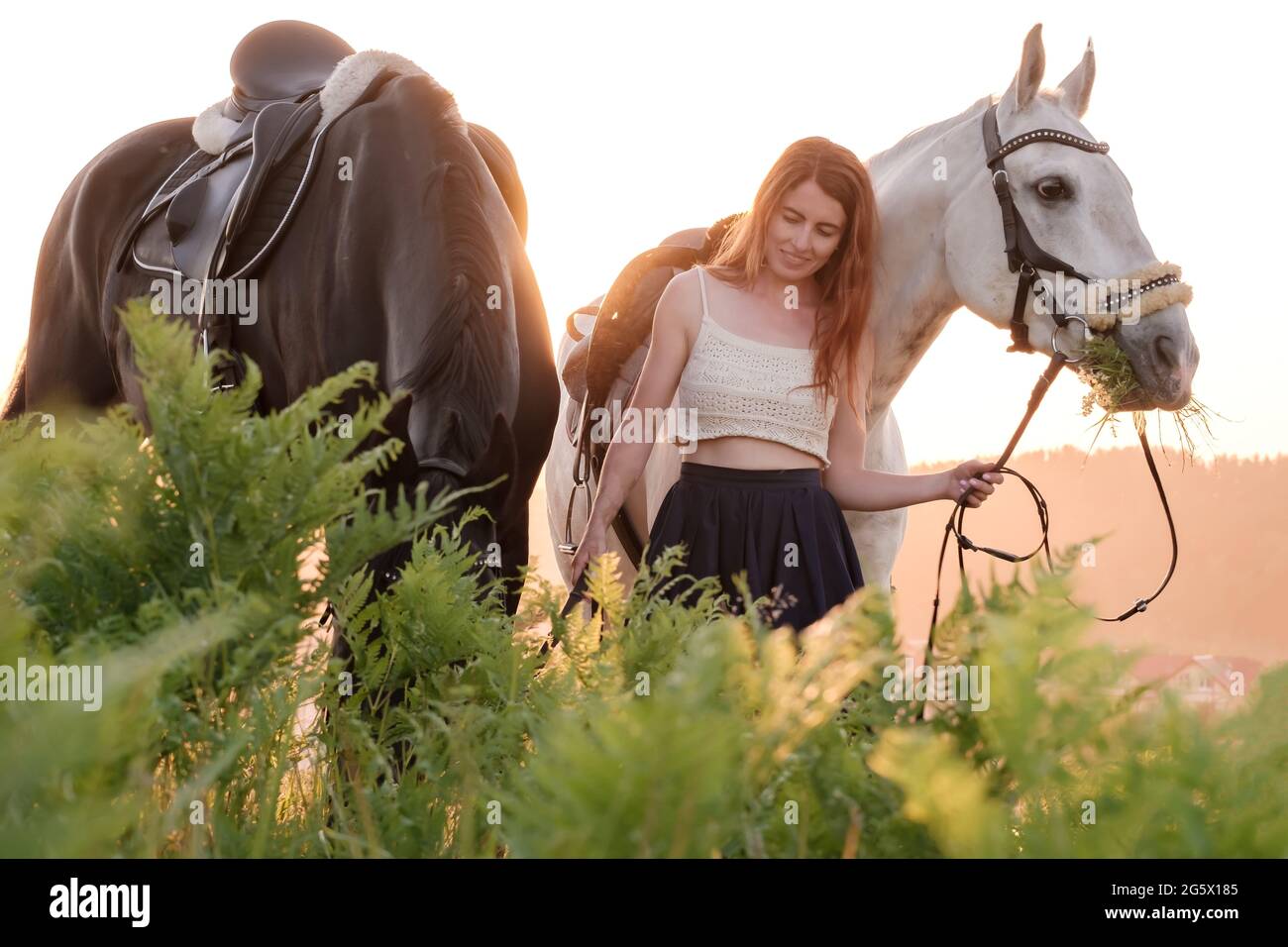 Smiling woman walking her two horses, holding them by the bridle ...