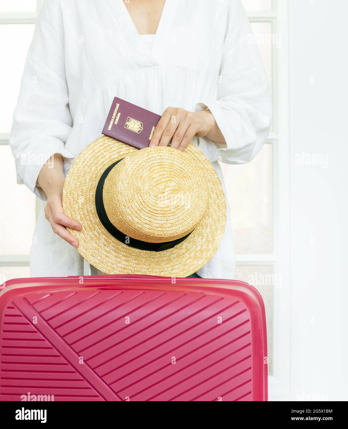 Woman with pink suitcase holds summer hat and Romanian passport and ...
