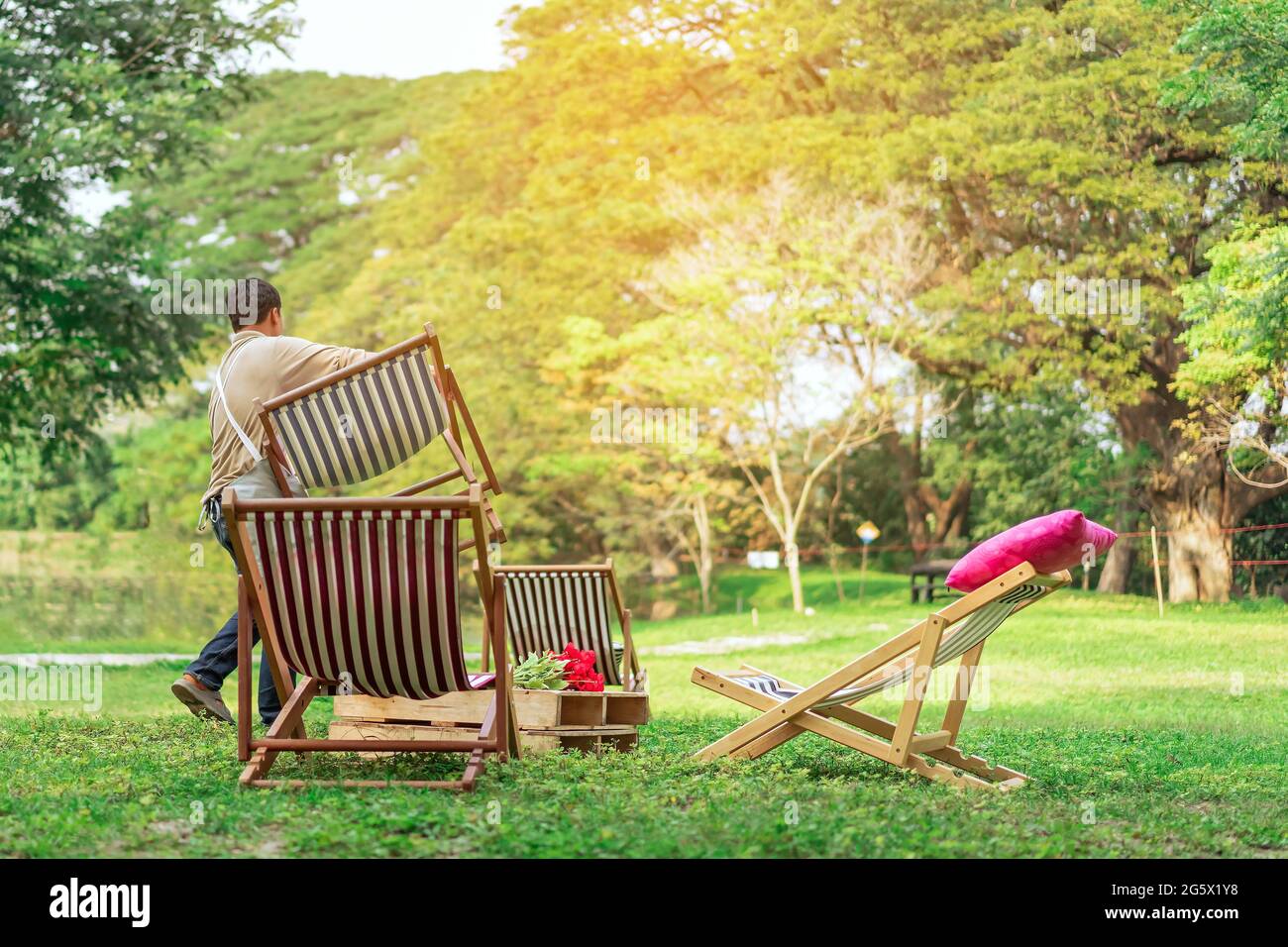 Back view of male waiter prepare deck chairs for customers to sit and ...