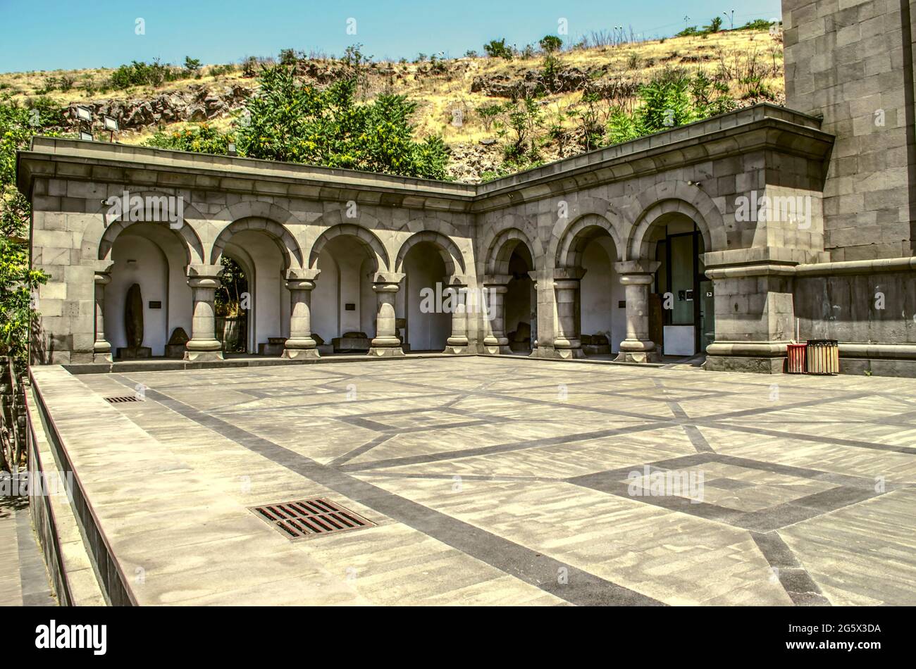 A basalt arched gallery with a courtyard laid with a pattern of light ...