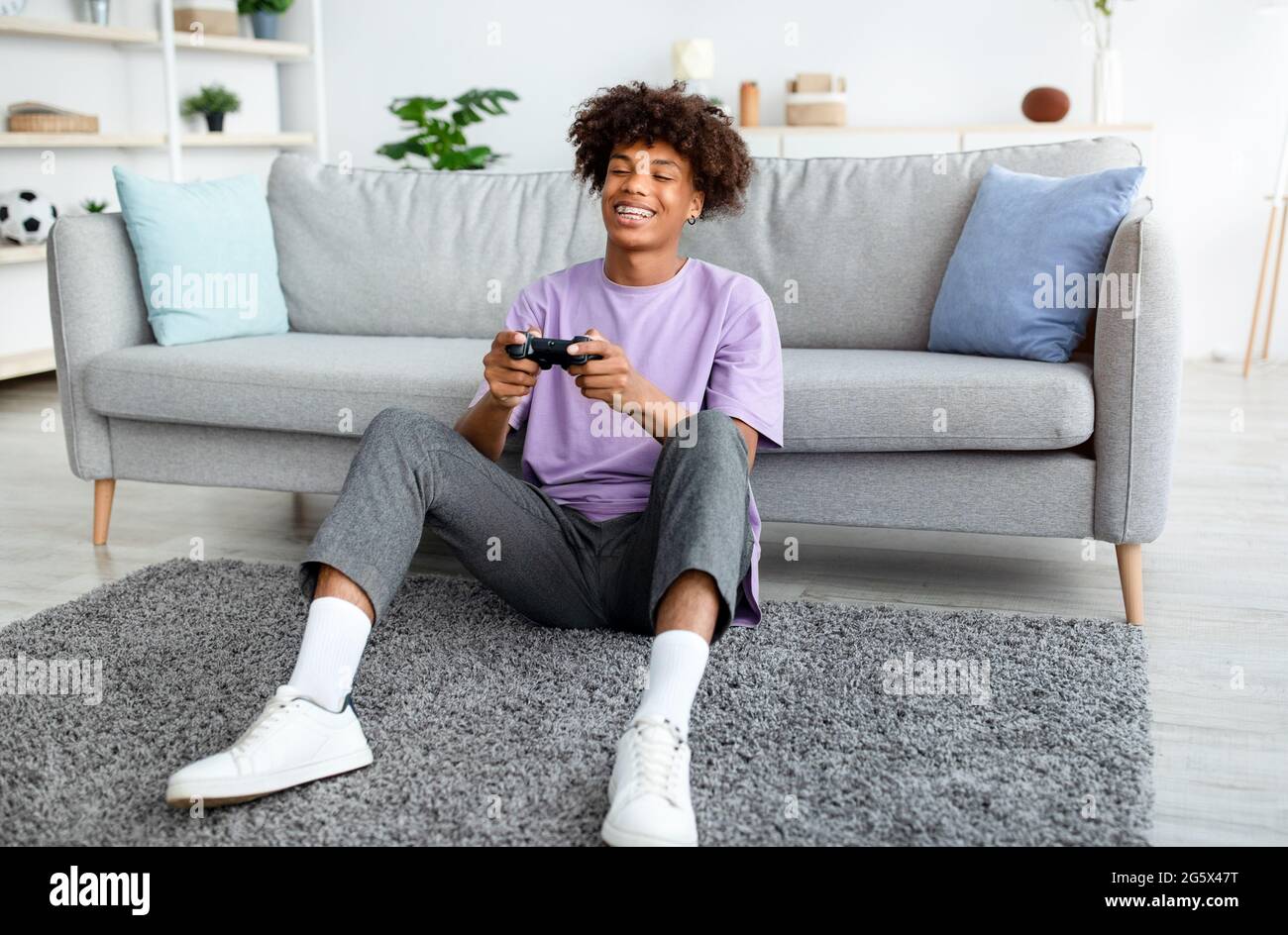 Happy black teenager enjoying videogame on playstation, having fun at ...