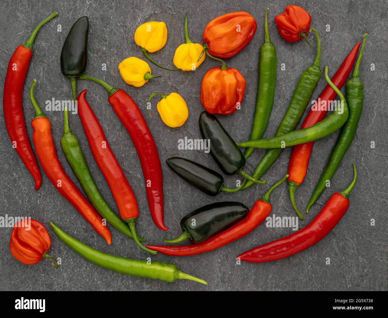 Plan view of assorted chilli peppers on grey background Stock Photo - Alamy