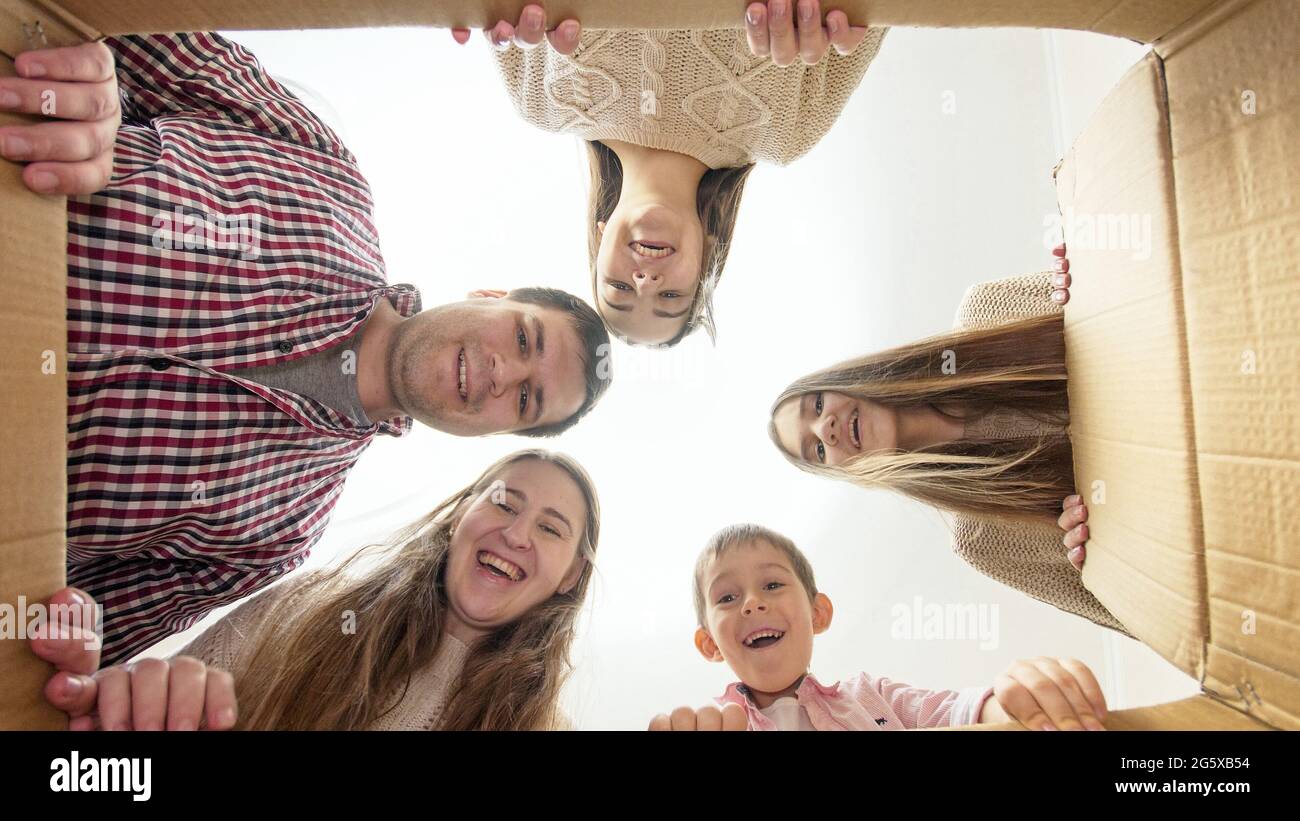 POV of happy big family opens big cardboard box and looking inside ...