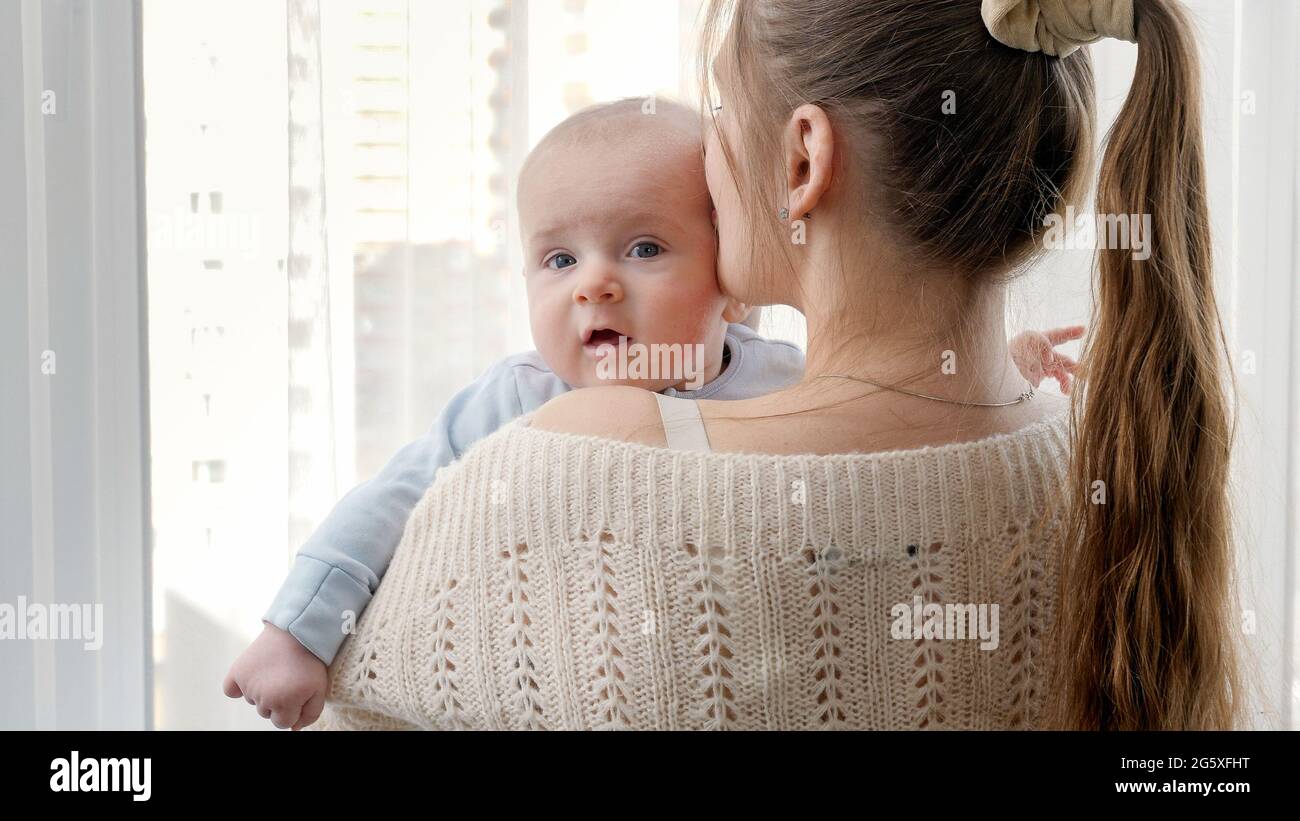 Portrait of adorable baby boy hugging mother and looking in camera ...