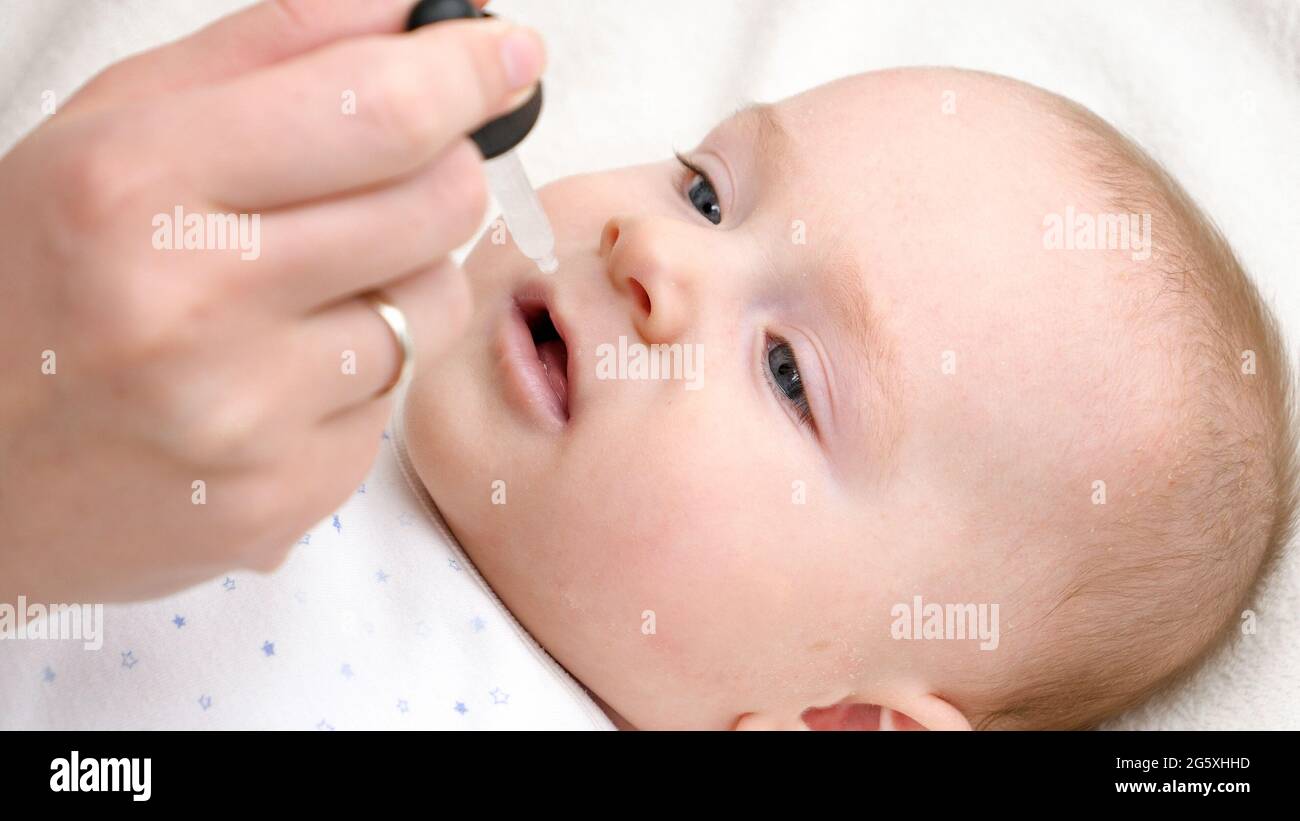 Closeup of little baby boy taking vitamin D from eyedropper. Concept of ...