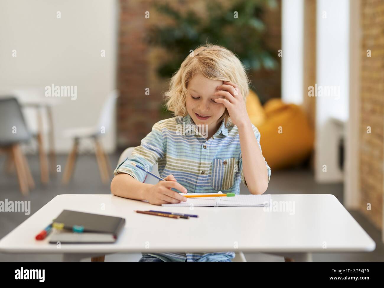 Solve equation. Diligent elementary school boy doing sums, writing in ...