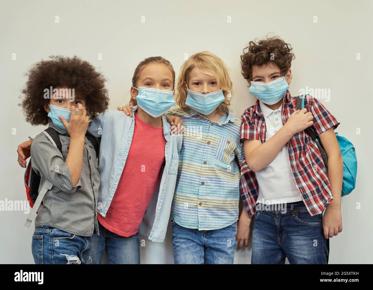 Four beautiful multinational children wearing protective face masks ...