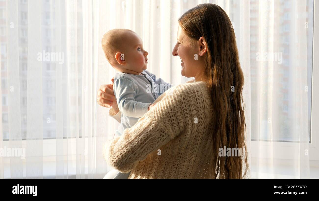 Cute baby looking at smiling mother at big endow in sunset light ...