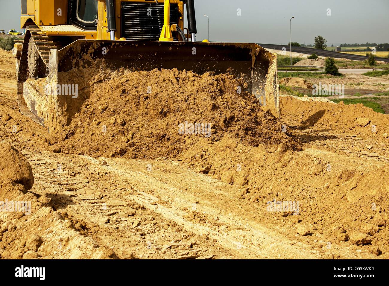 Asphalt road construction process. The bulldozer levels and compacts ...