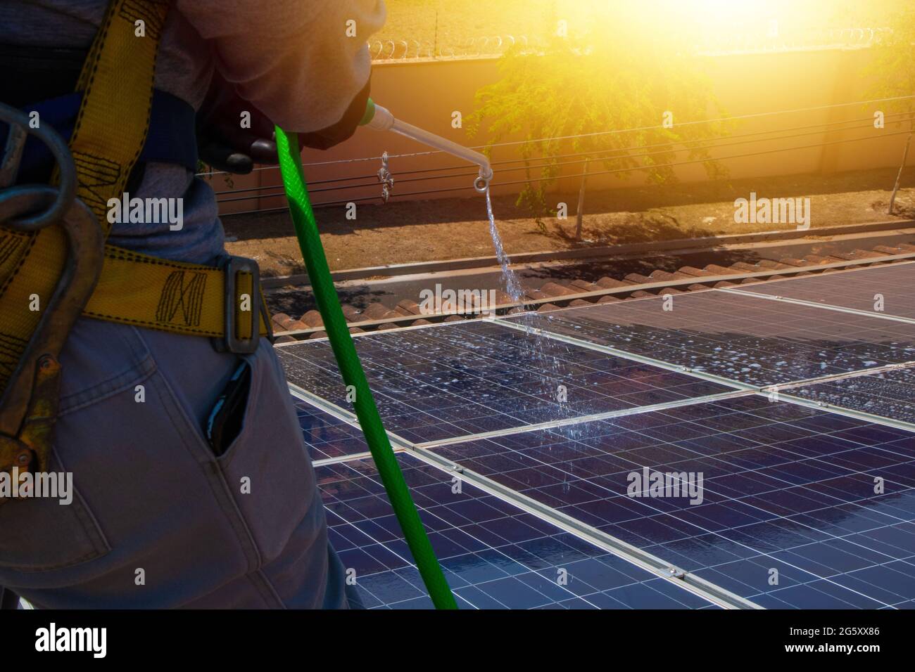 Solar worker cleaning photovoltaic panels with brush and water ...