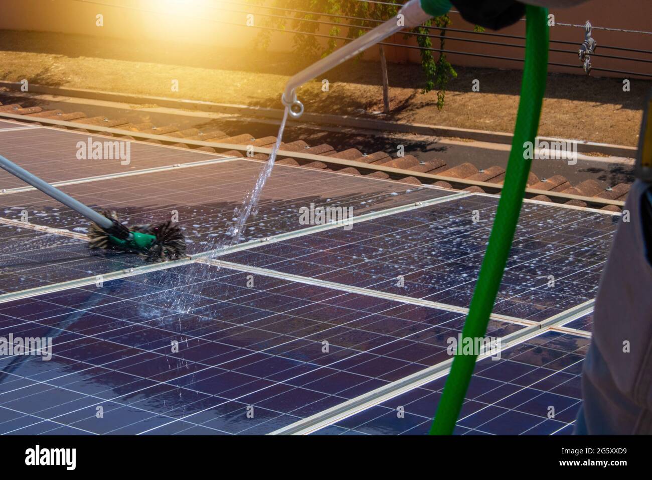 Solar worker cleaning photovoltaic panels with brush and water ...