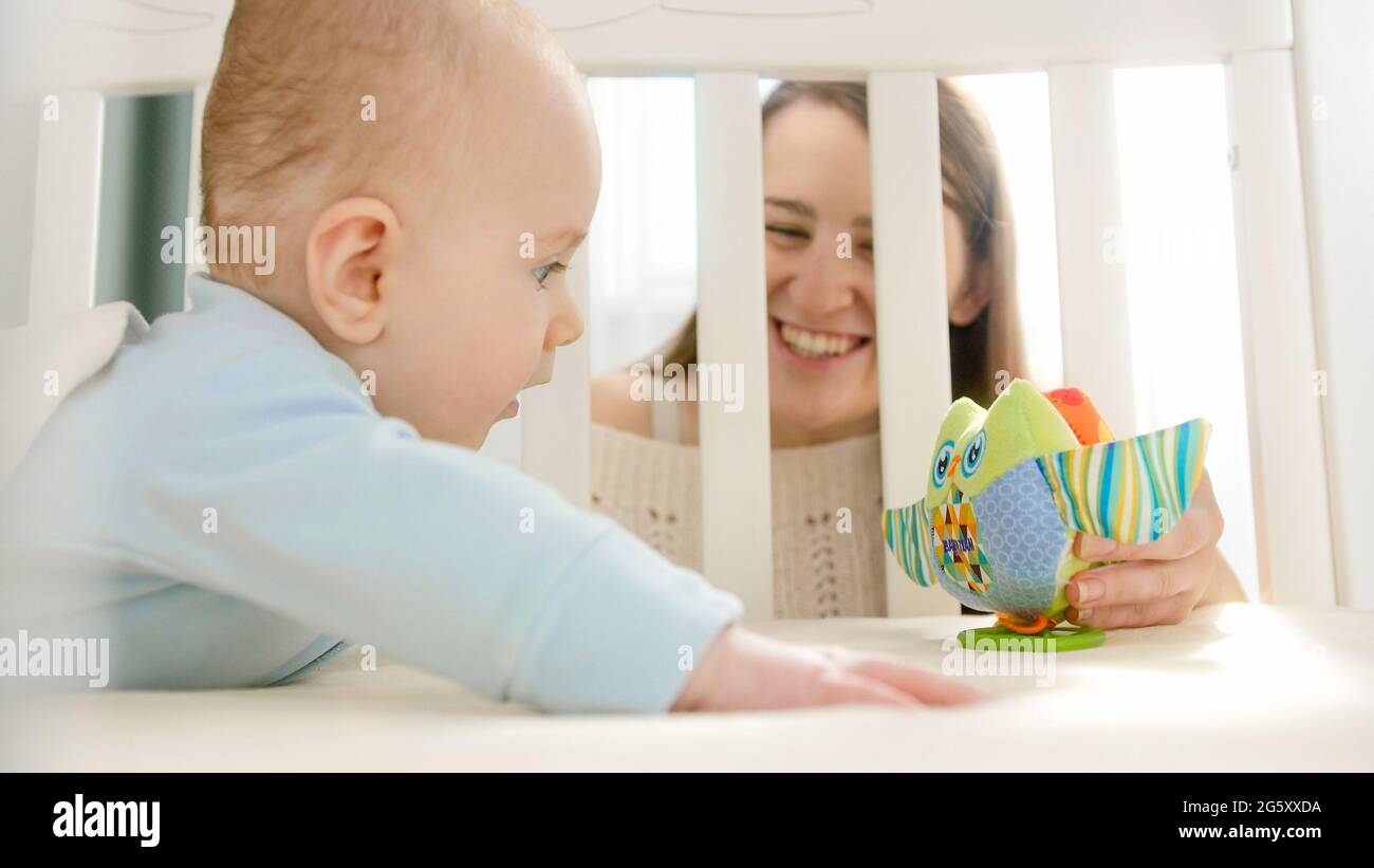 Little baby crawling in cradle and reaching for colorful toy. Concept ...