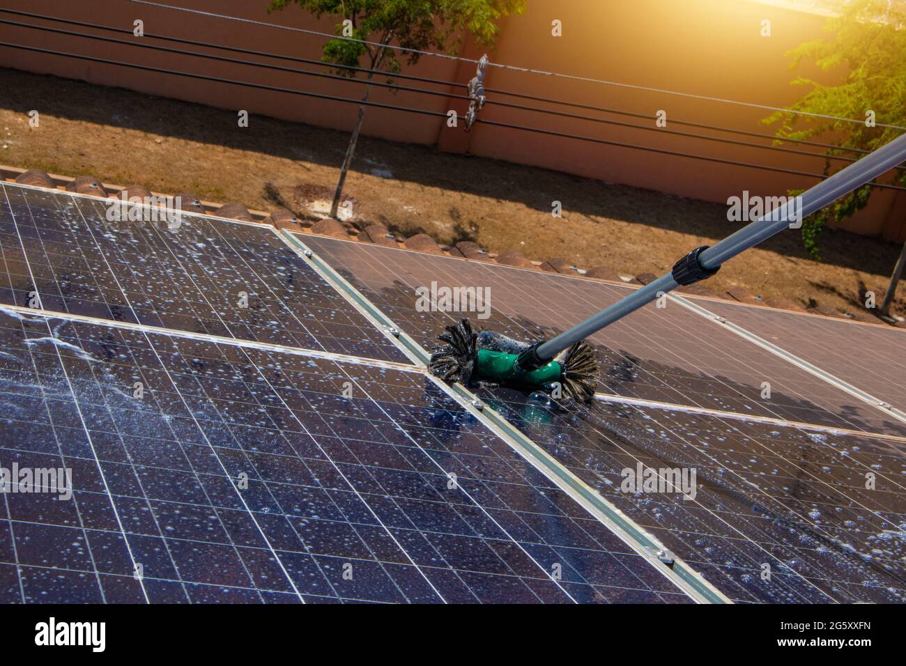 Solar worker cleaning photovoltaic panels with brush and water ...