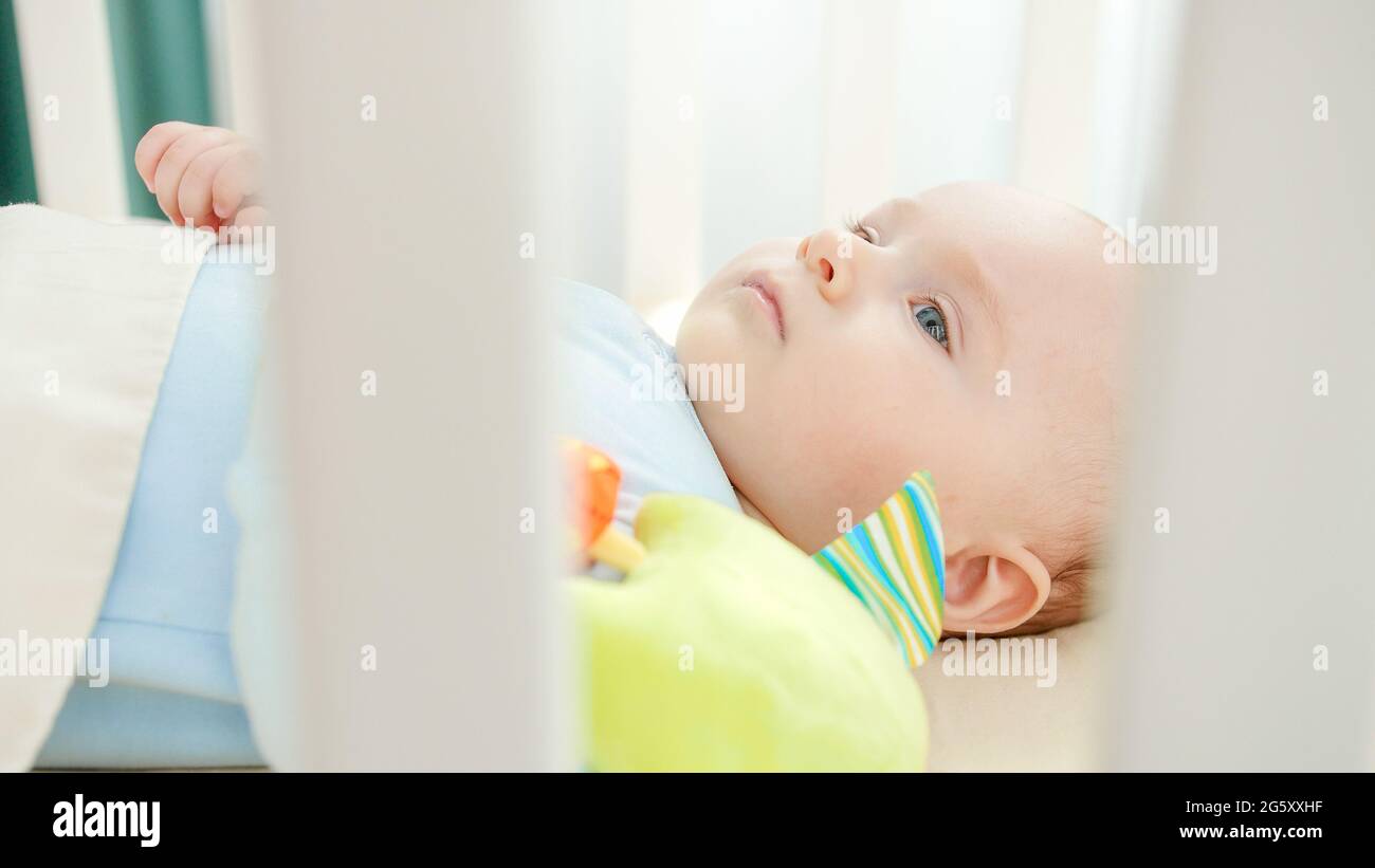 View through banister on little baby playing with toy in cradle ...