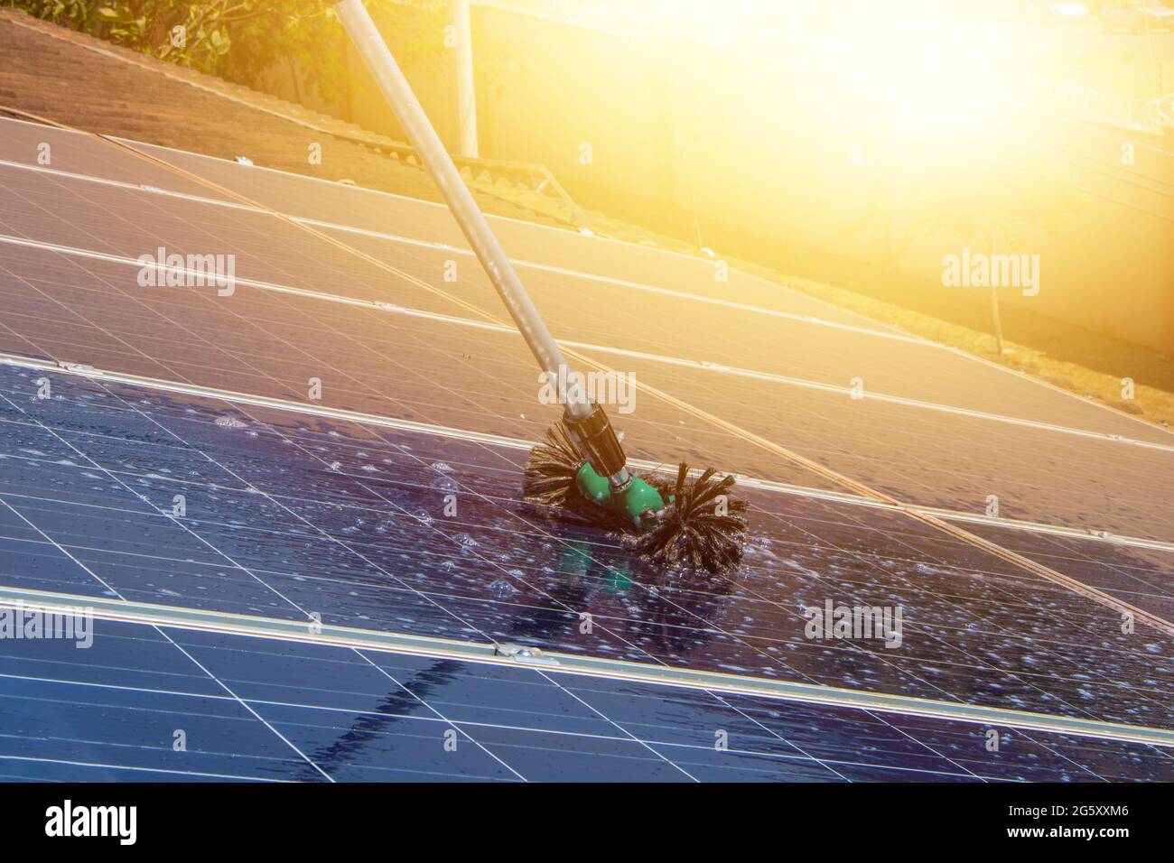 Solar worker cleaning photovoltaic panels with brush and water ...