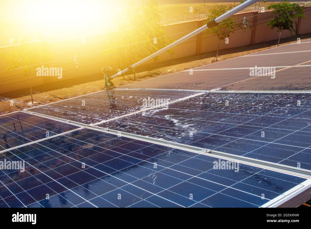 Solar worker cleaning photovoltaic panels with brush and water ...