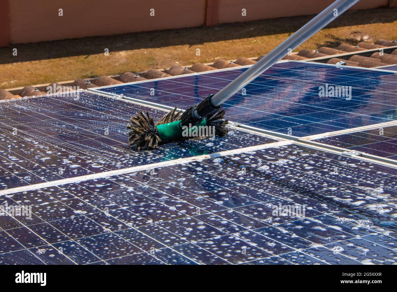 Solar worker cleaning photovoltaic panels with brush and water ...