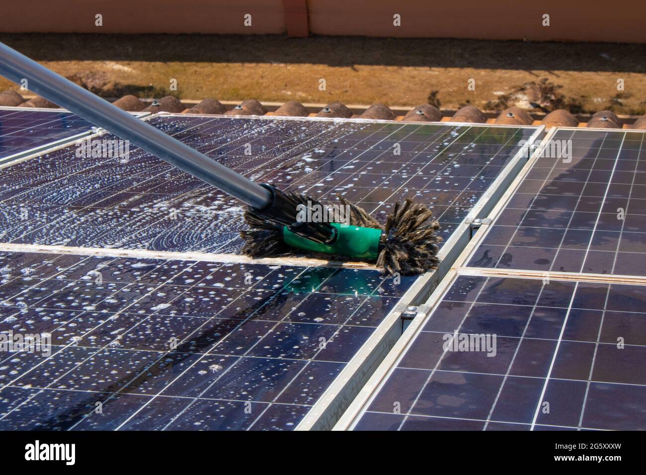 Solar worker cleaning photovoltaic panels with brush and water ...