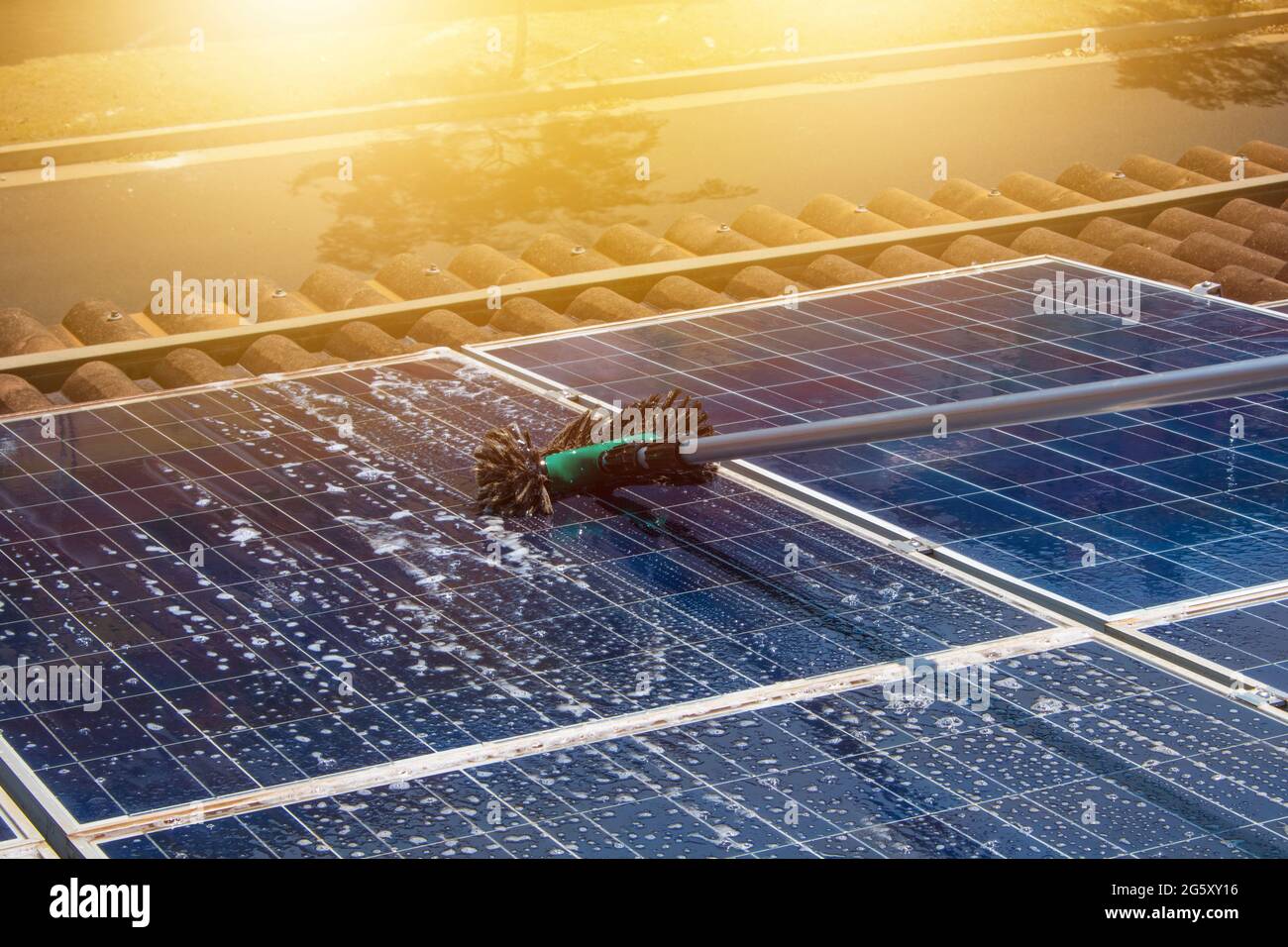 Solar worker cleaning photovoltaic panels with brush and water ...