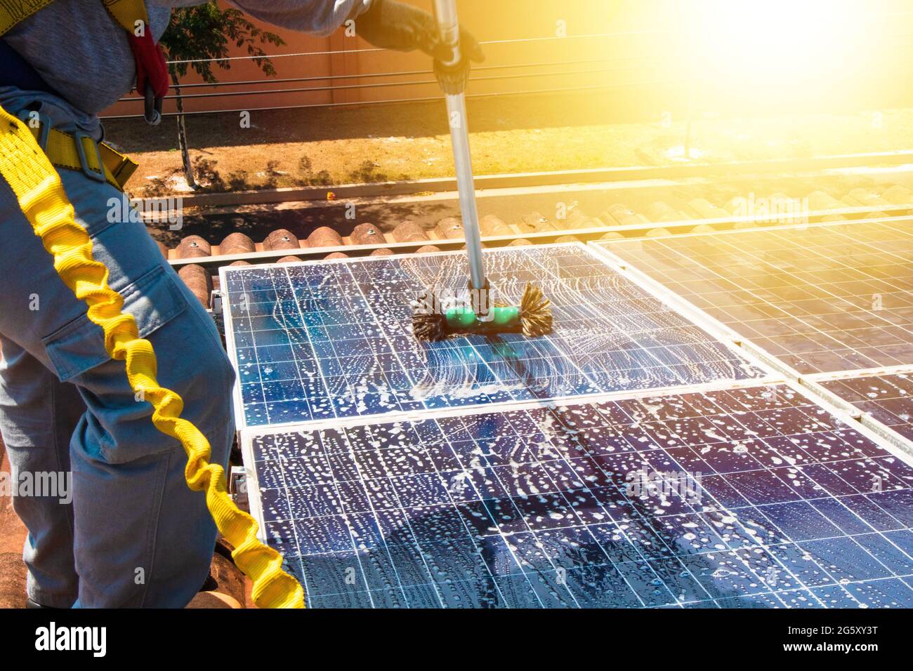 Solar worker cleaning photovoltaic panels with brush and water ...