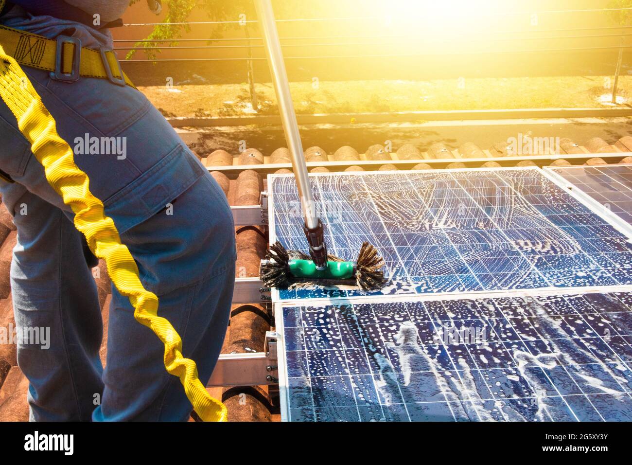 Solar worker cleaning photovoltaic panels with brush and water ...