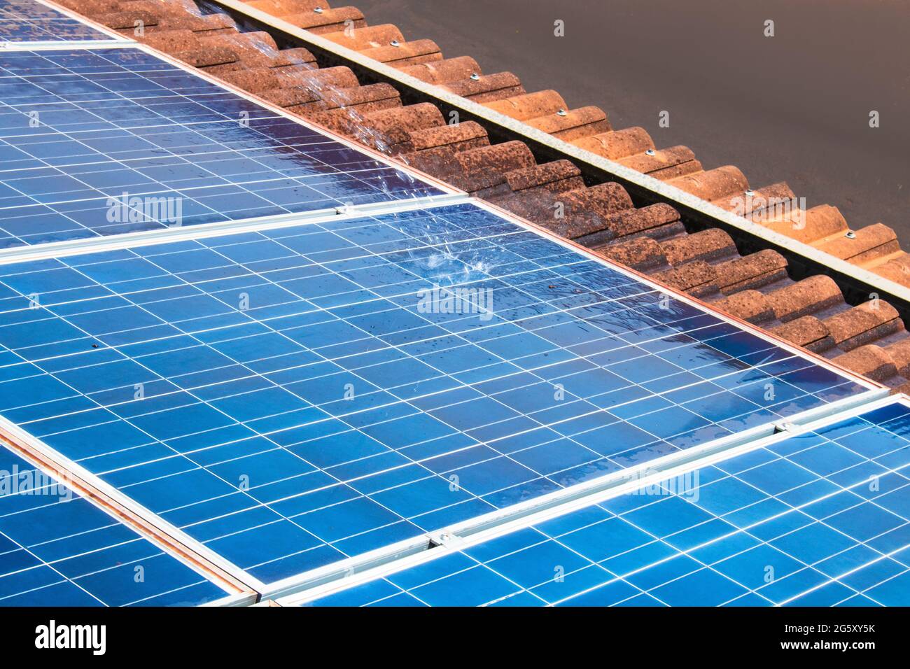 Solar worker cleaning photovoltaic panels with brush and water ...
