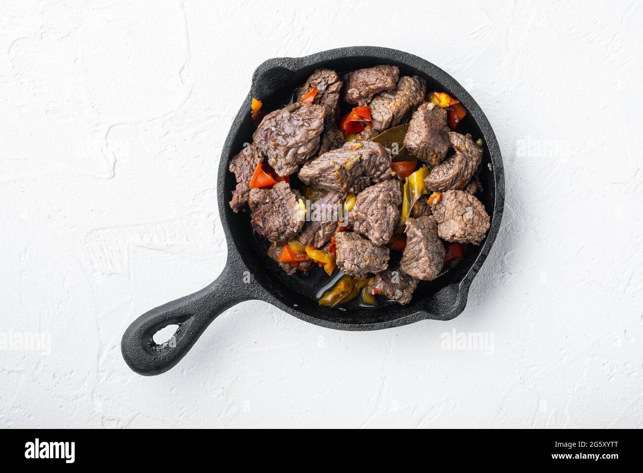 Goulash, beef stew set, in cast iron frying pan, on white stone surface ...