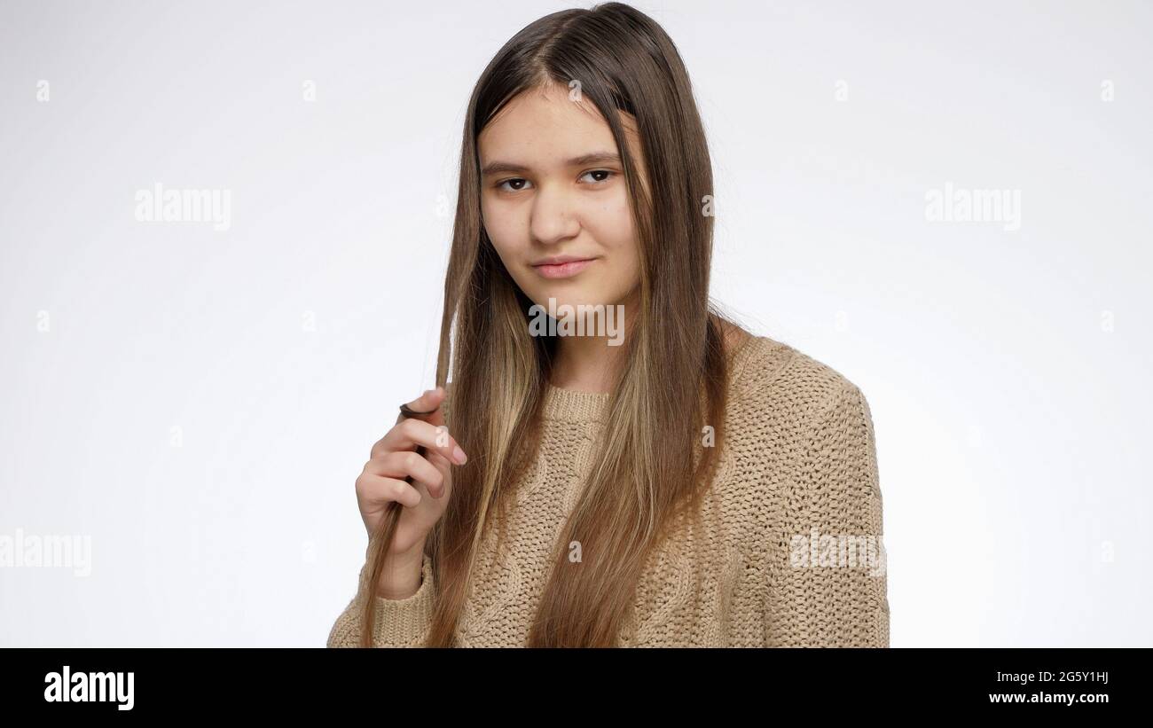 Beautiful charming girl twisting long hair on finger and smiling in ...