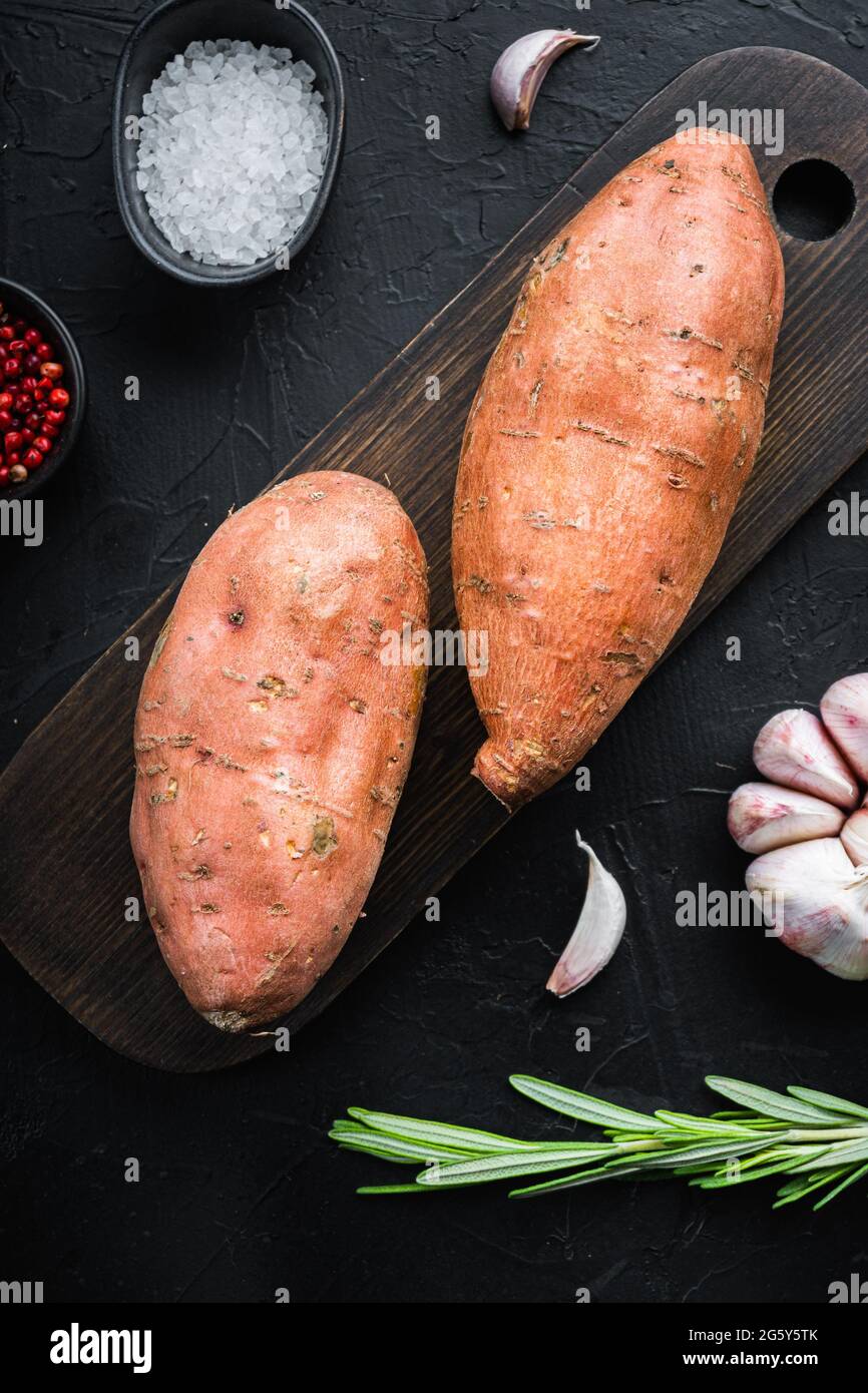 Sweet potato or batat with herbs and spices on black background, top ...