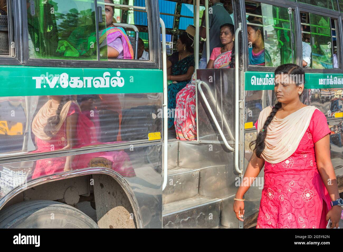 Exterior shot of thoughtful Indian female wearing sari walking past bus ...