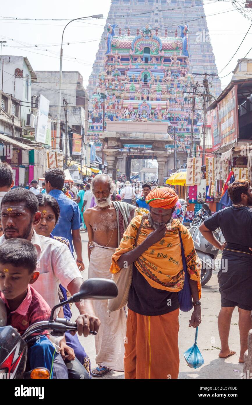 Hindu sadhu dressed in orange robes in front of gopura of Sri ...
