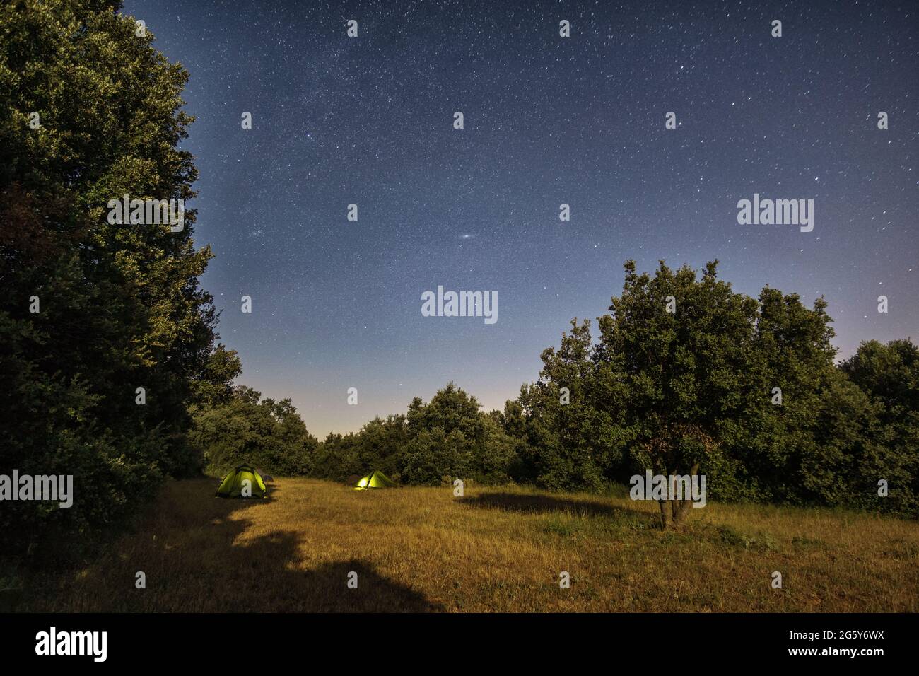 Landscape with meadow and tents at night in the moonlight with ...