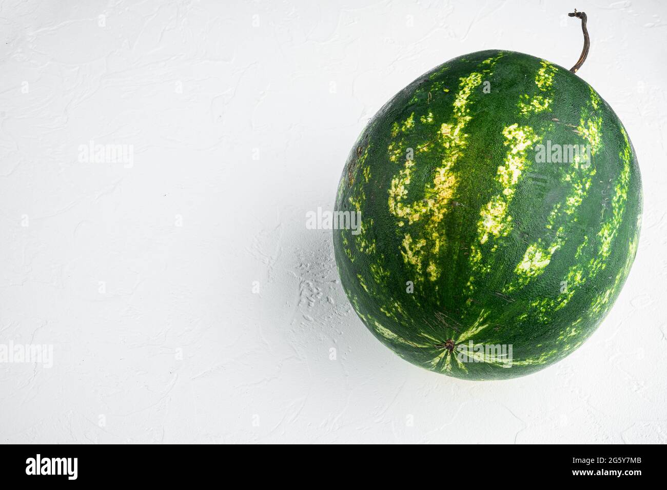 Single watermelon set, on white stone table background, with copy space ...