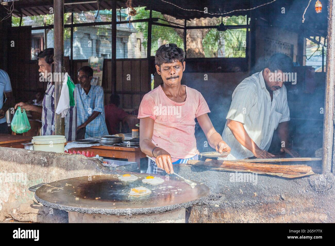 Indian chef with moustache cooks fried eggs on traditional hot plate in ...