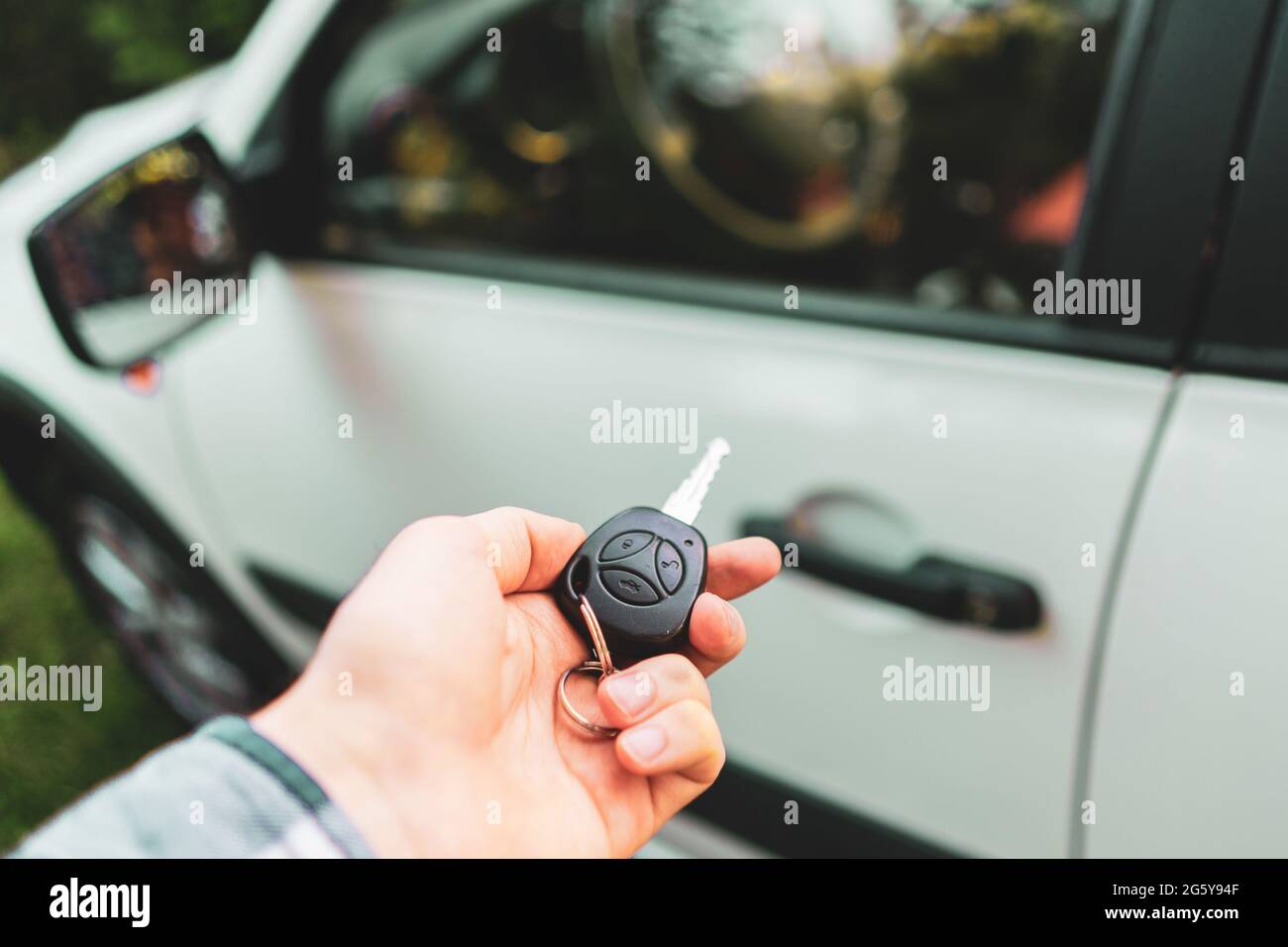driver hand holding a wireless remote control keys to open the car ...