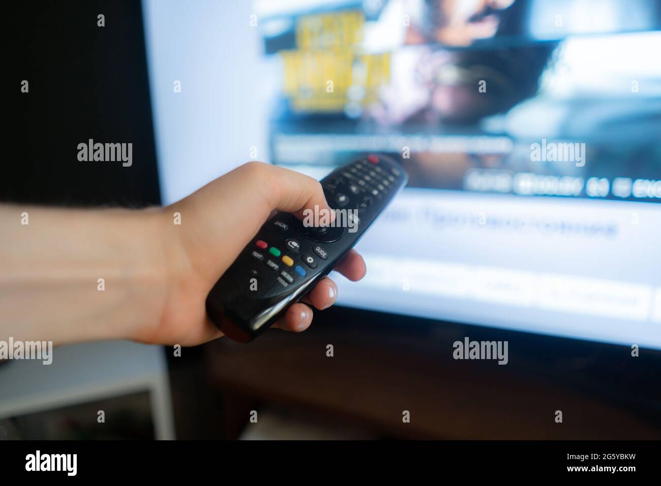 hand holding a tv remote, swithing media chanels screen Stock Photo - Alamy