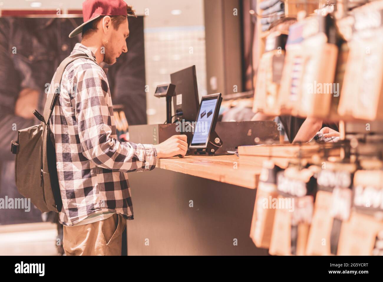 young man making a purchase and paying at the cash deck in the store ...