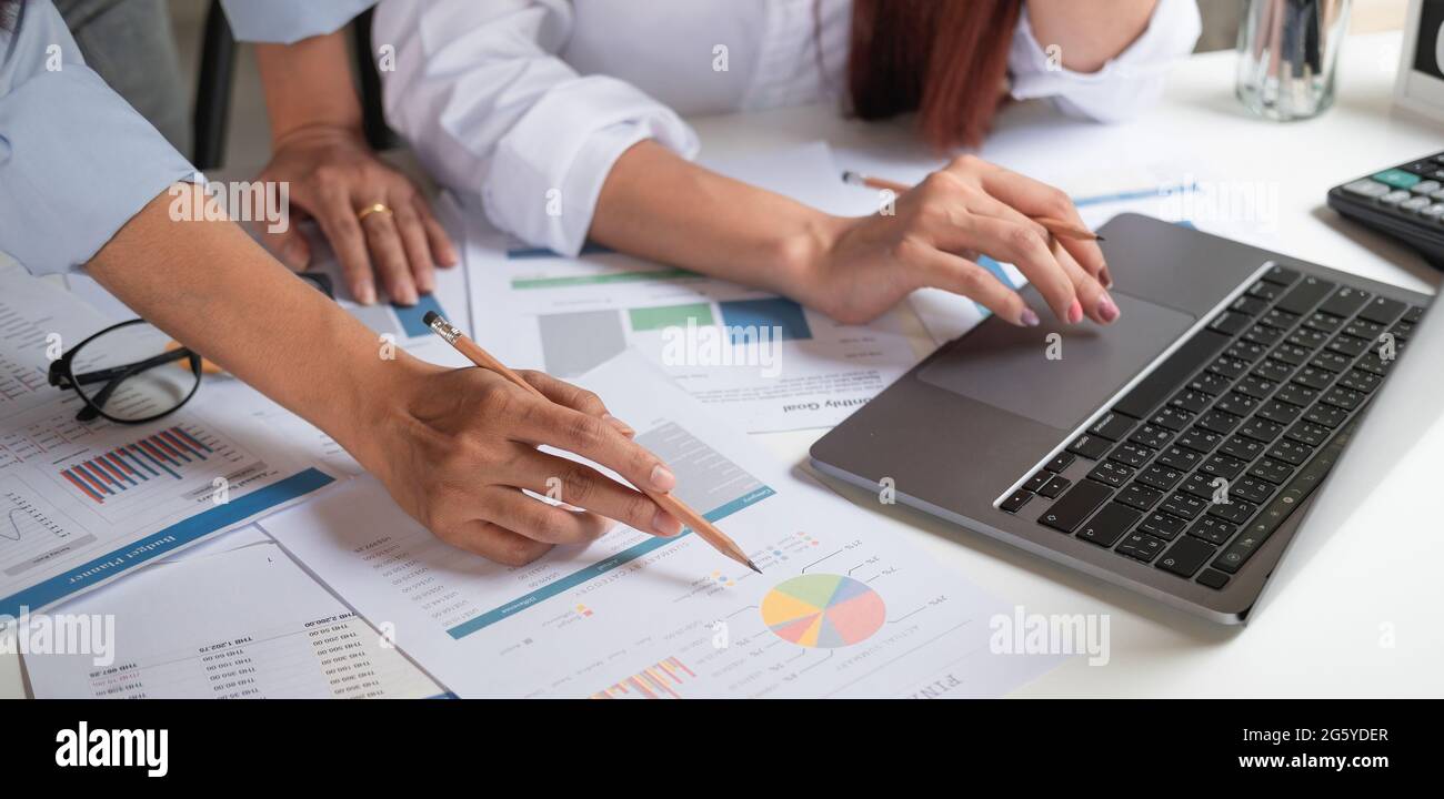 Close up business team using a calculator and laptop computer to ...
