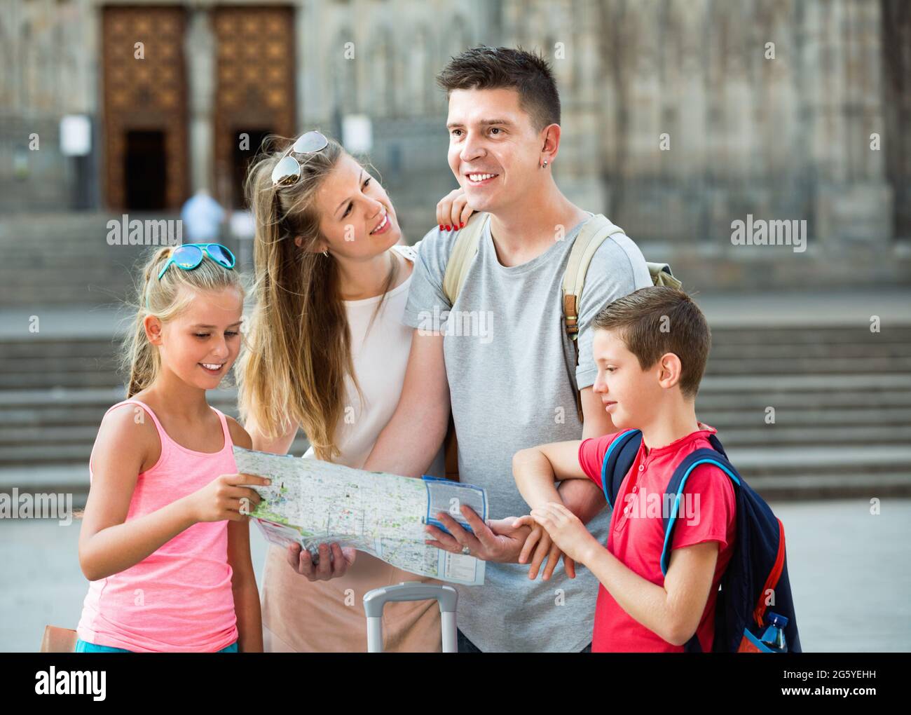 Parents with two kids traveling together searching location on paper ...
