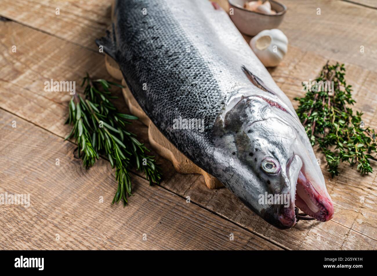 Raw marine salmon fish on a wooden kichen table with herbs. Wooden ...